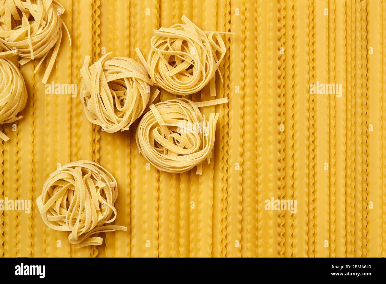 dry pasta tagliatelle and mafaldini warm background Stock Photo - Alamy