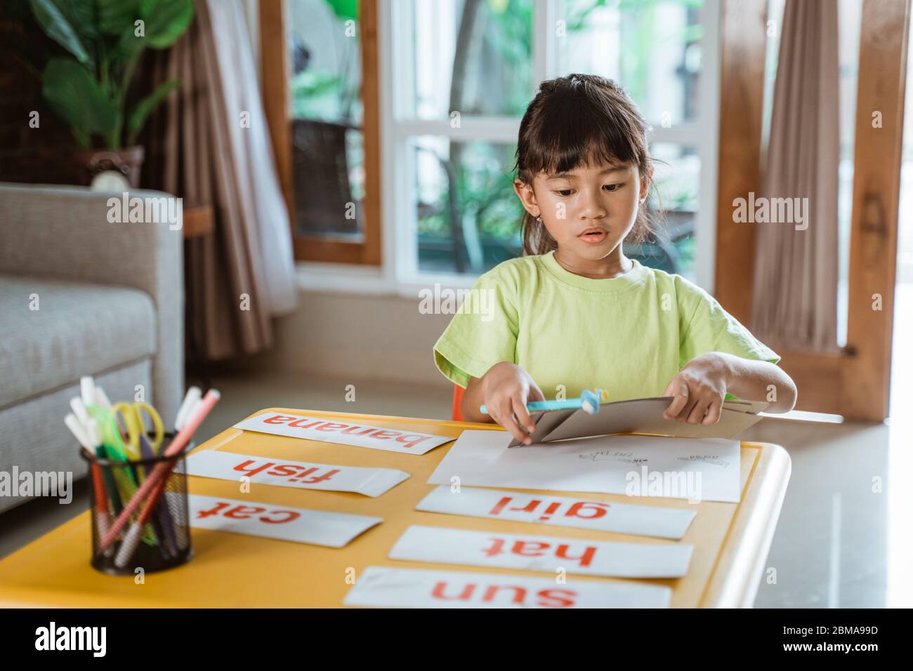 little girl learning to read by herself at home. kid studying alone ...
