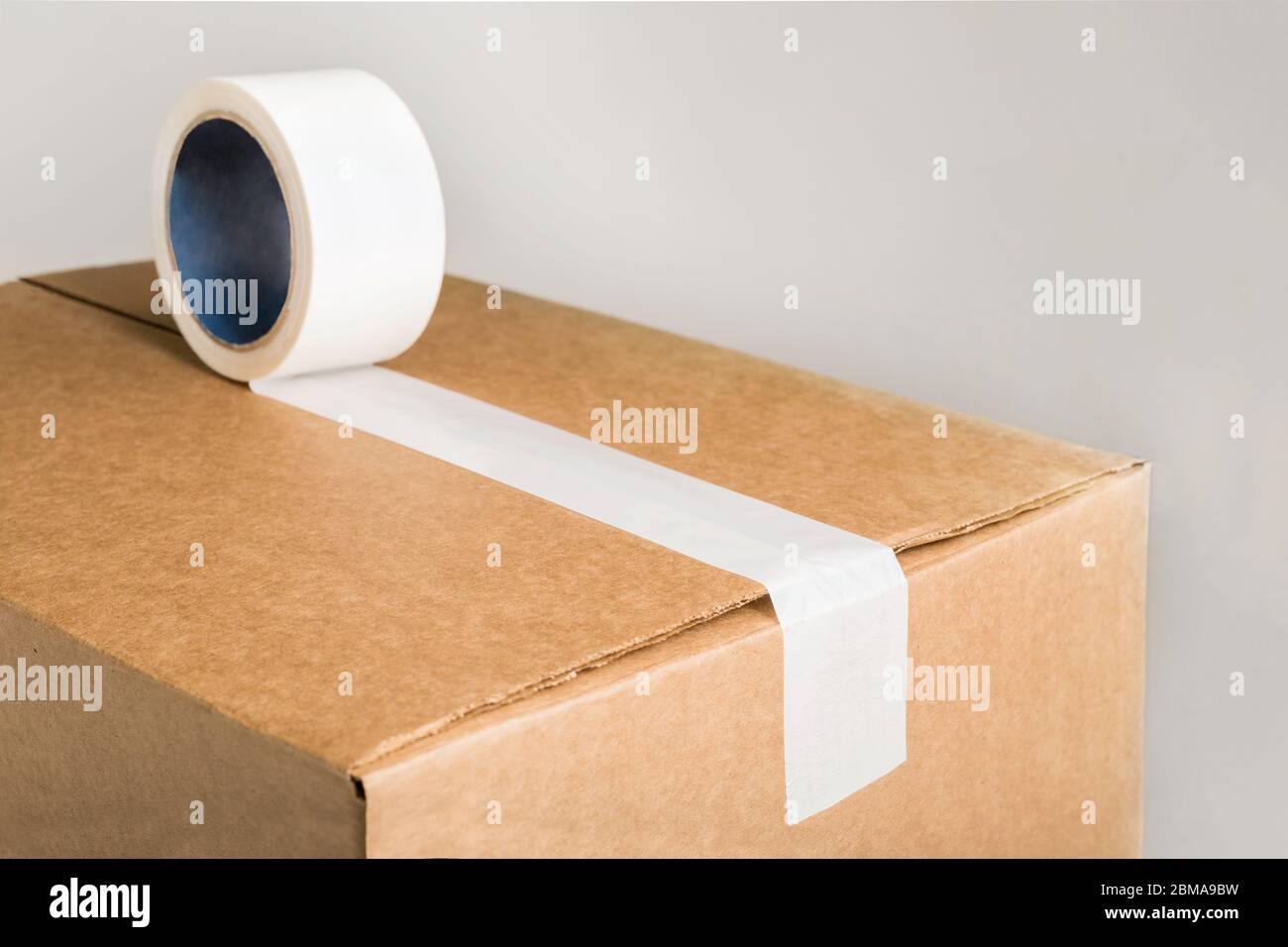 Corrugared brown cardboard box with white adhesive tape Stock Photo - Alamy