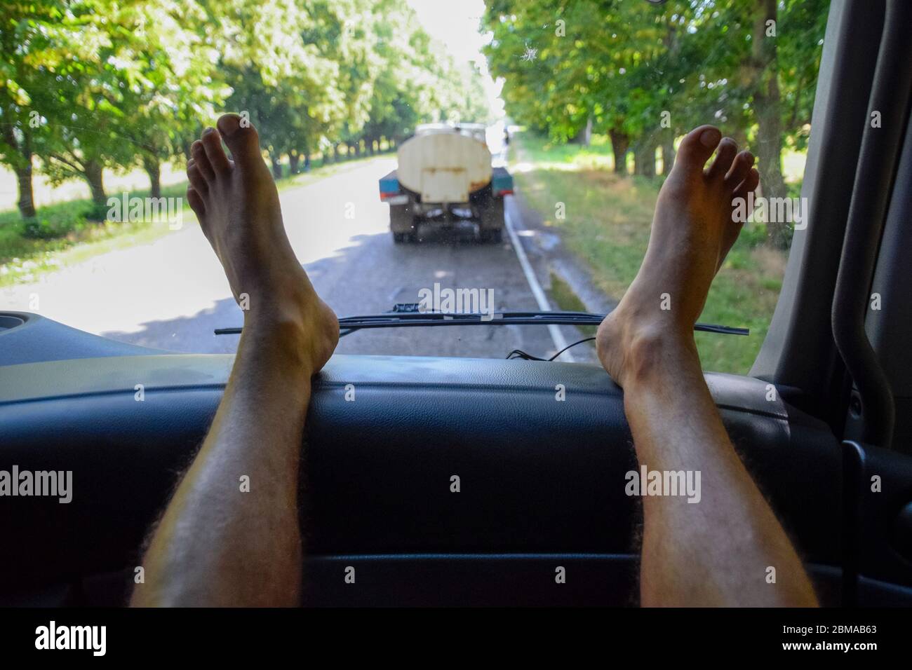The passenger put his feet on the panel in the car. rest in the car ...