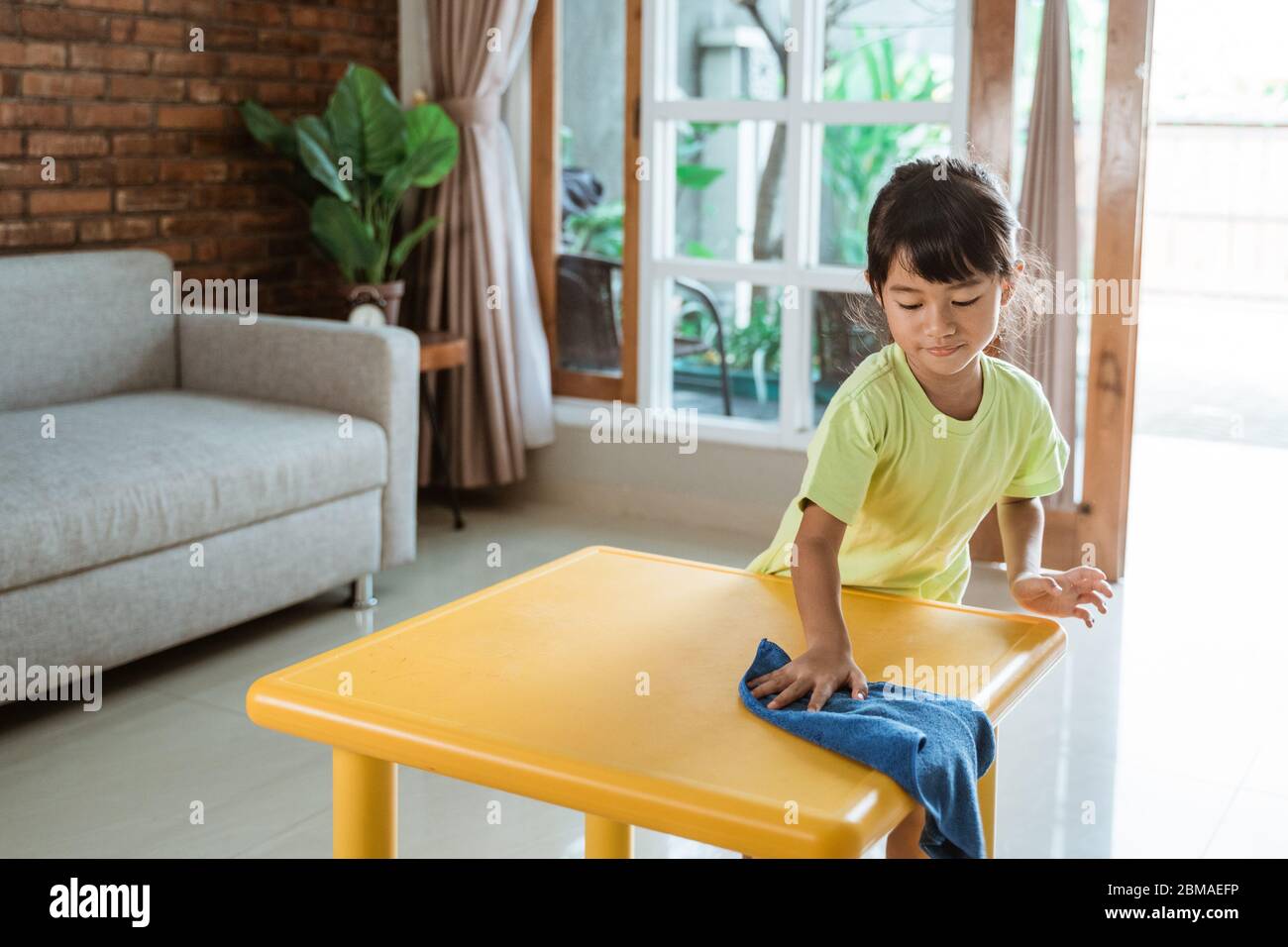 little kid cleaning up the table by herself Stock Photo - Alamy