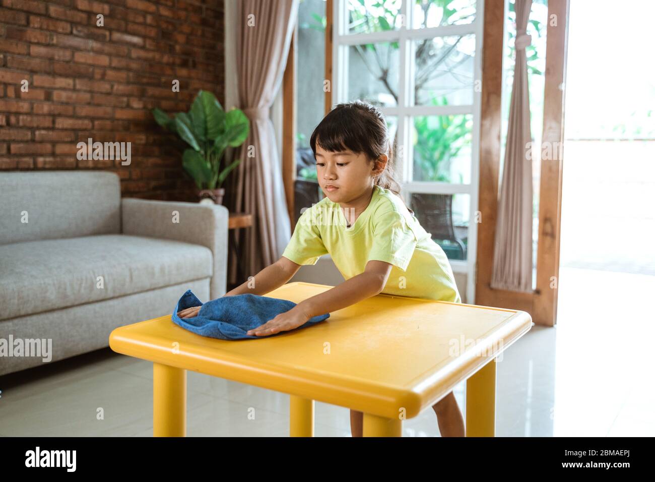 little kid cleaning up the table by herself Stock Photo - Alamy