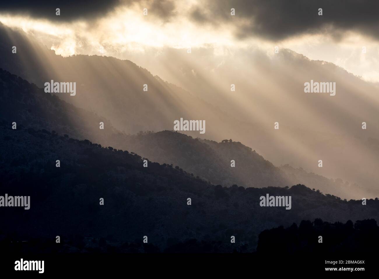 Sun rays piercing dark clouds over mountains in Crete, Greece Stock ...