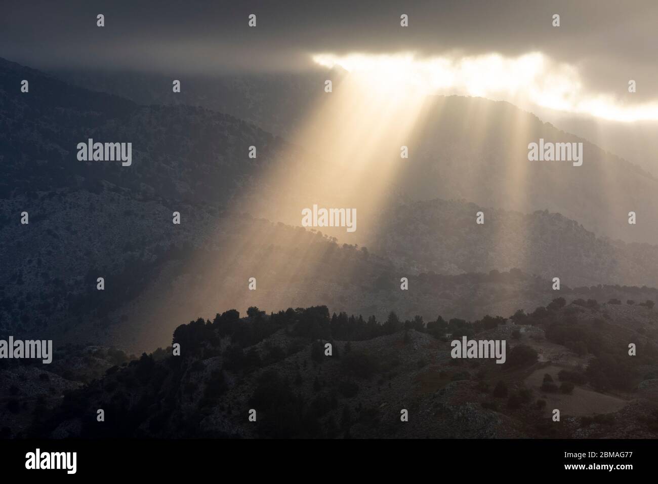 Sun rays piercing dark clouds over mountains in Crete, Greece Stock ...