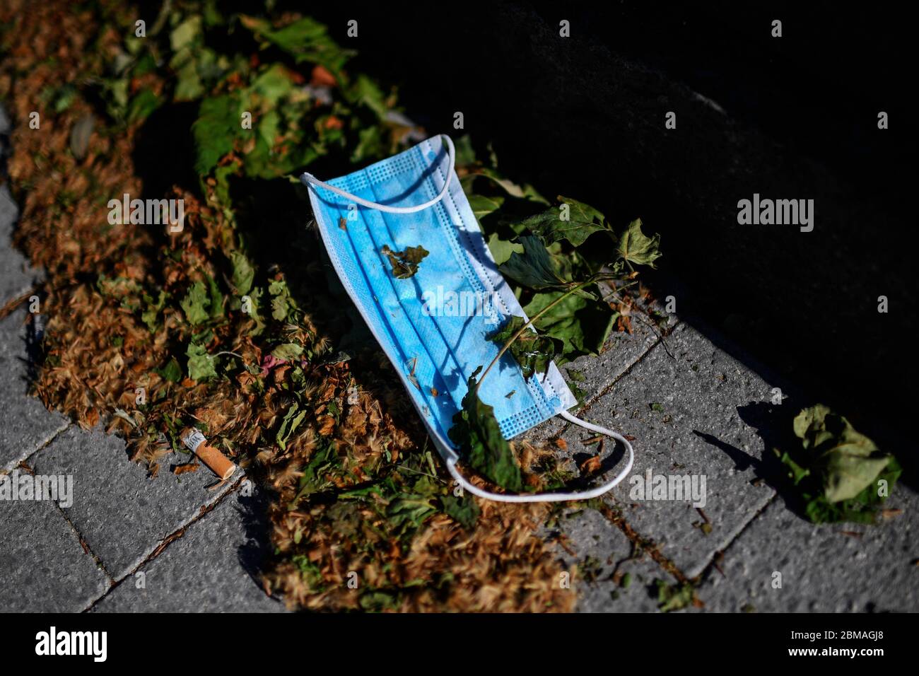 An obviously worn-out mouth and nose protection mask lies thrown away ...