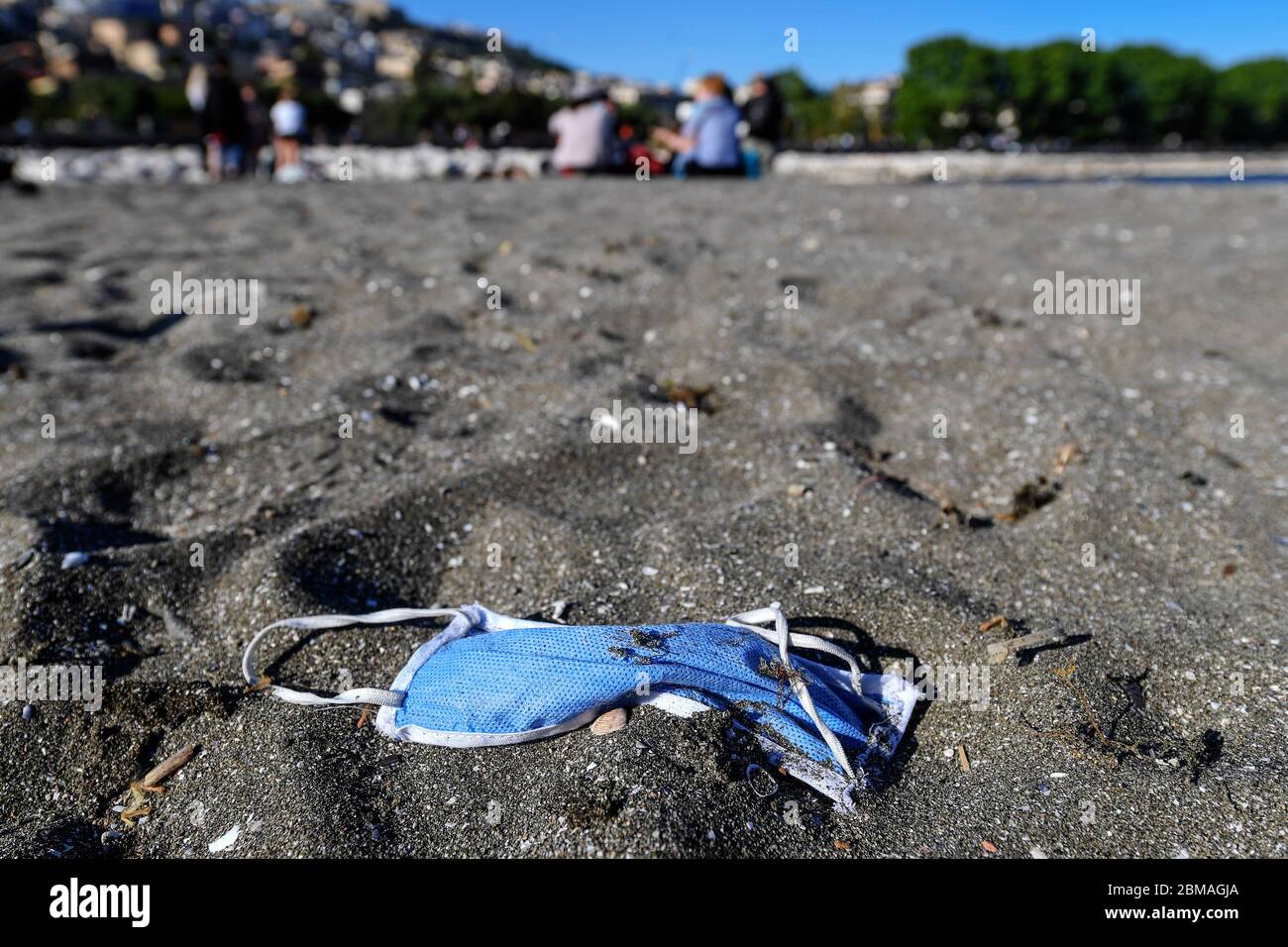 An obviously worn-out mouth and nose protection mask lies thrown away ...