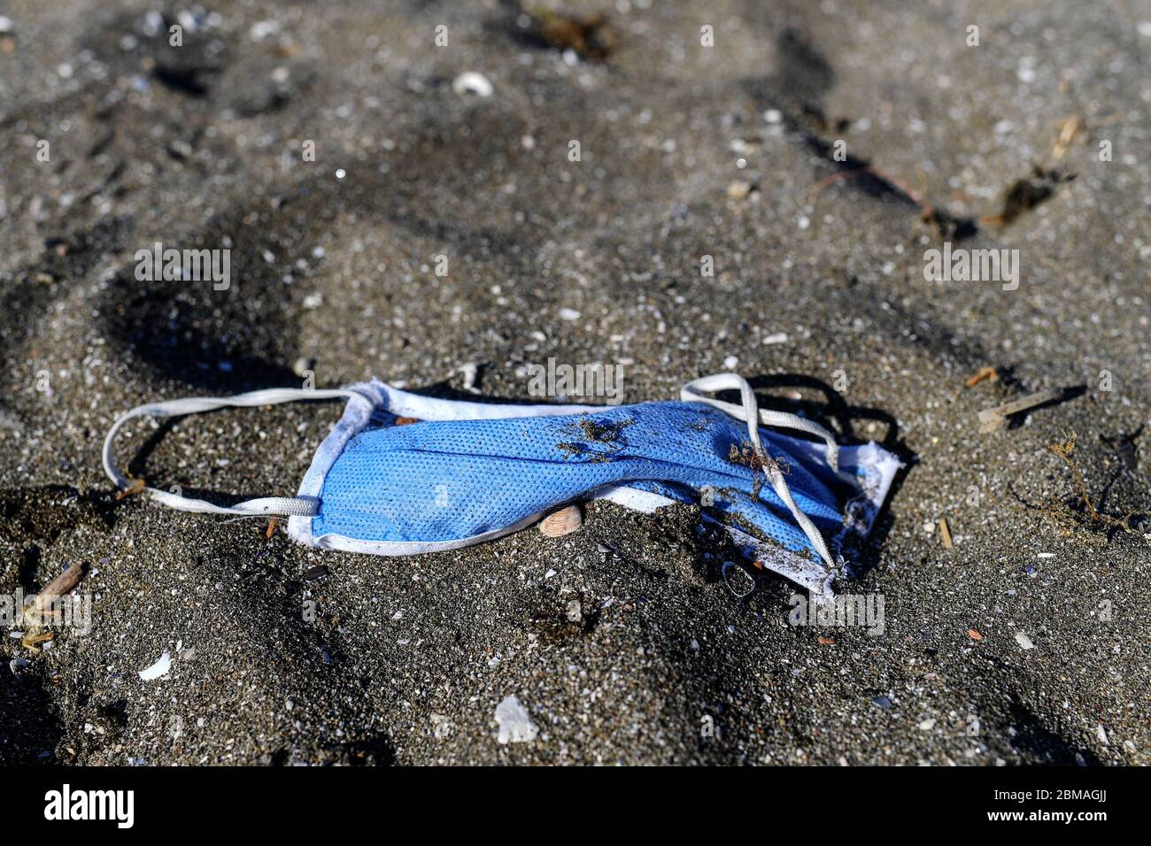 An obviously worn-out mouth and nose protection mask lies thrown away ...