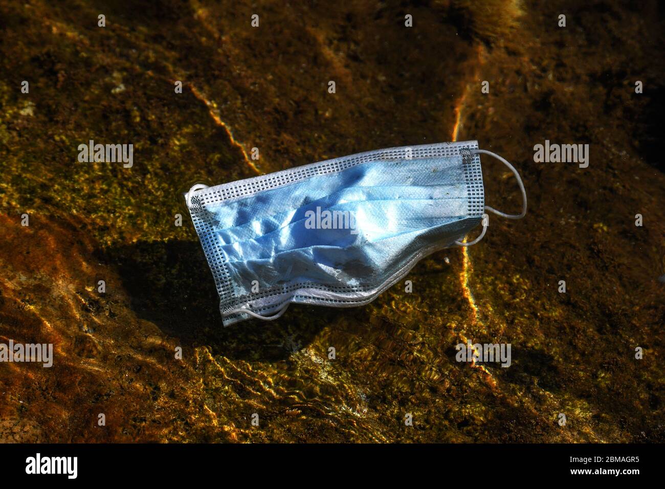 A protective mask for the mouth and nose thrown into the sea of the ...