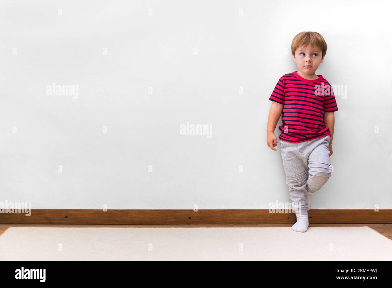 Boy with a rogue face and leaning against the wall. White background ...