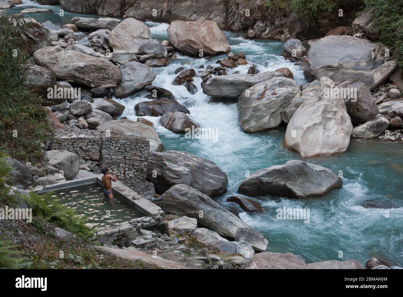 Man having bath in natural hot springs pool and turquoise glacial rocky ...