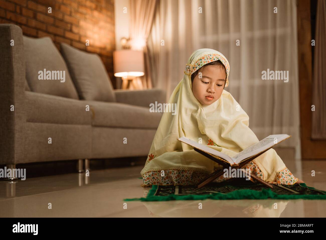 cute asian girl reading quran by herself at home. muslim toddler with ...