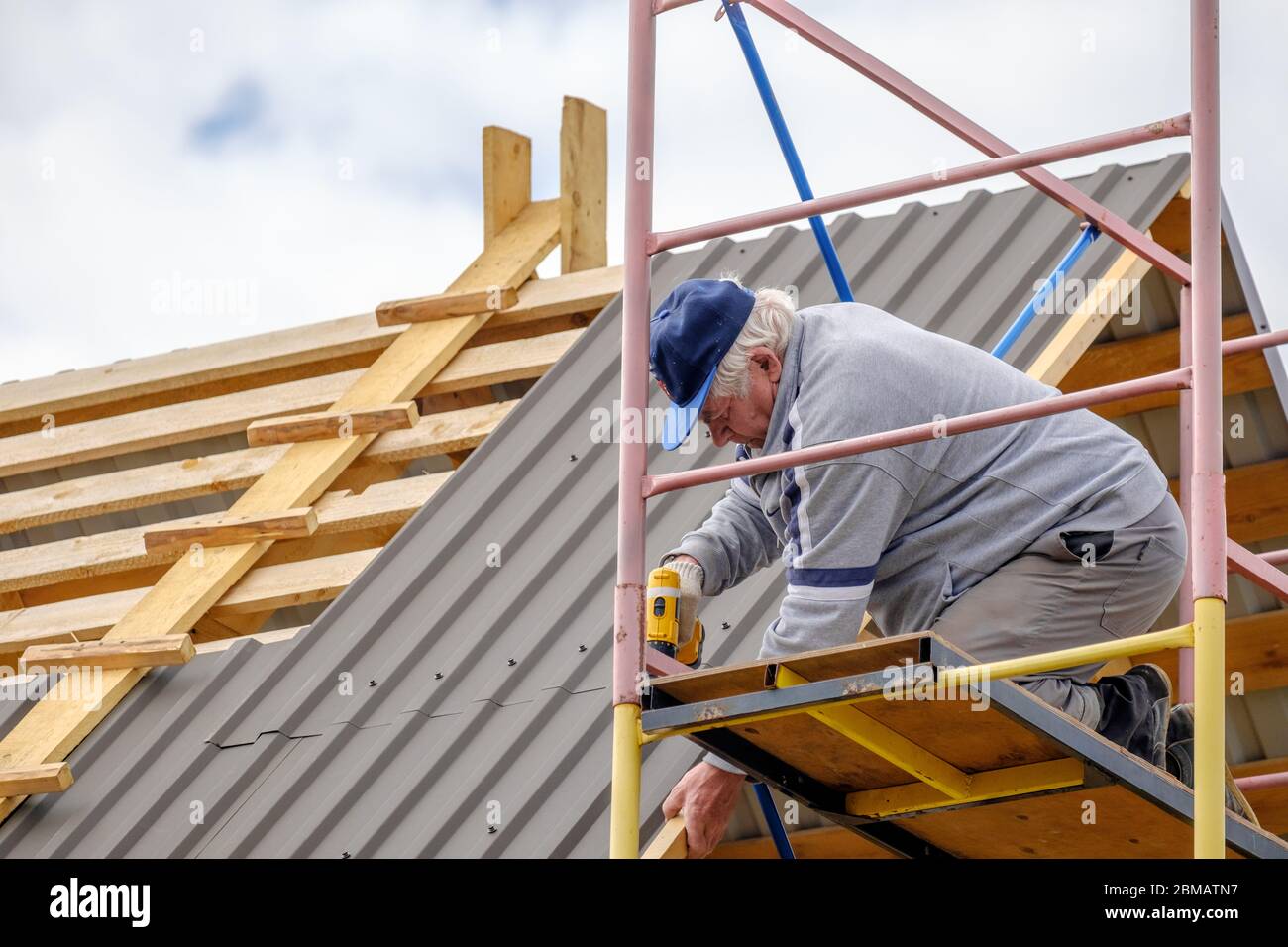 Senior gray-haired Construction man using a screwdriver, fastens a ...