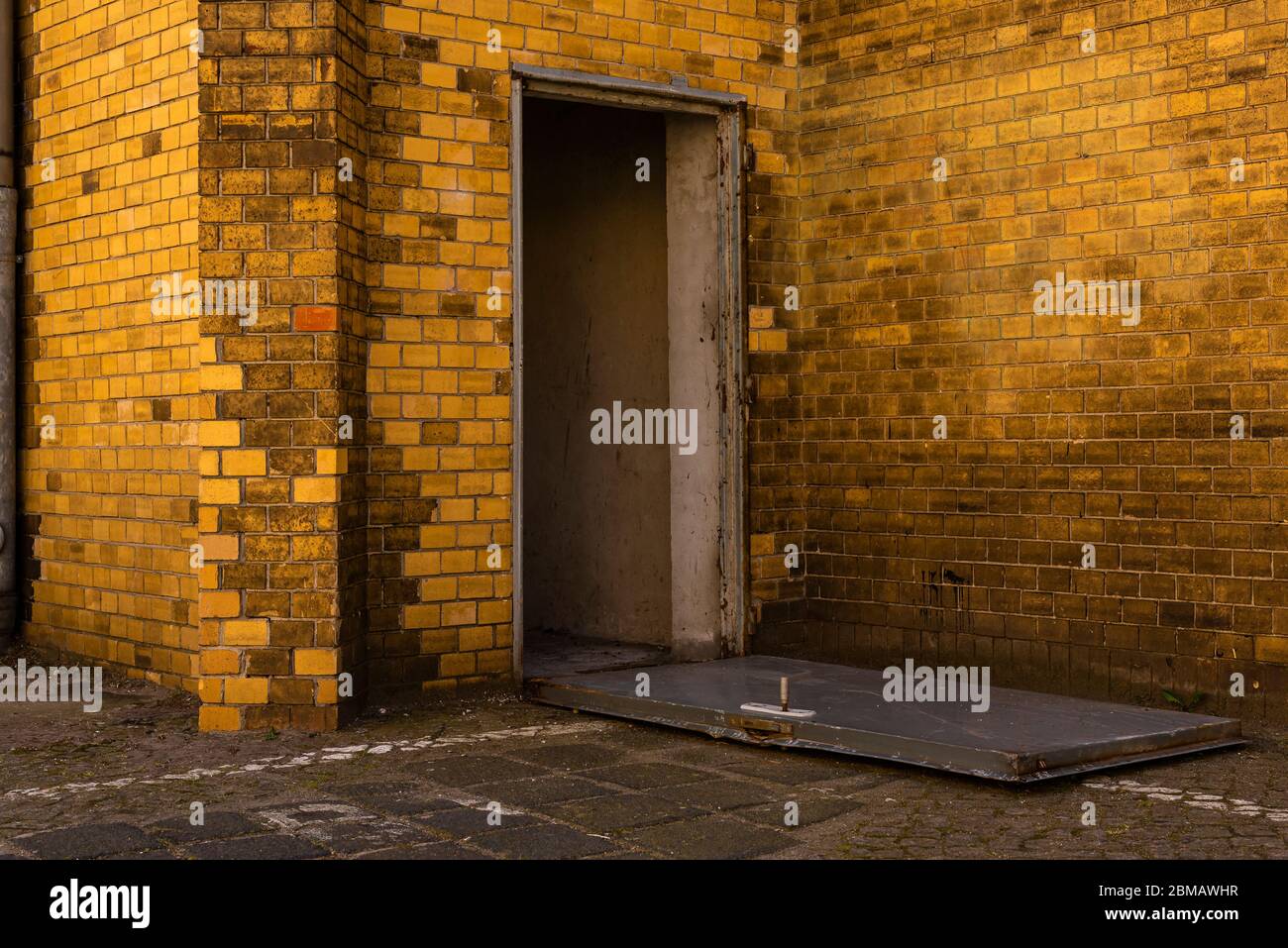 A door has fallen out of the door frame, brick facade with a broken ...