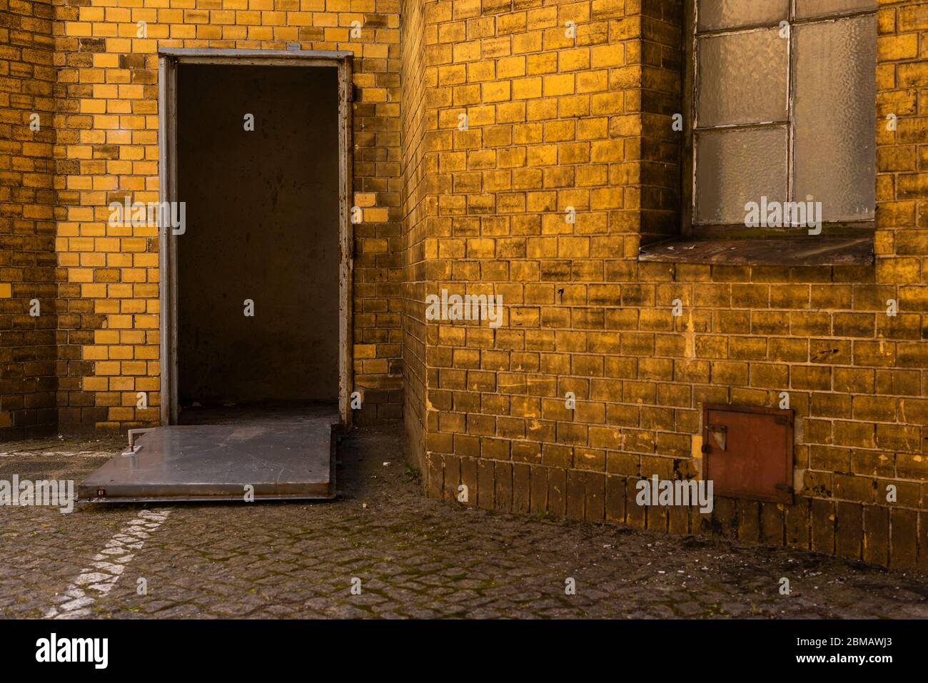 A door has fallen out of the door frame, brick facade with a broken ...