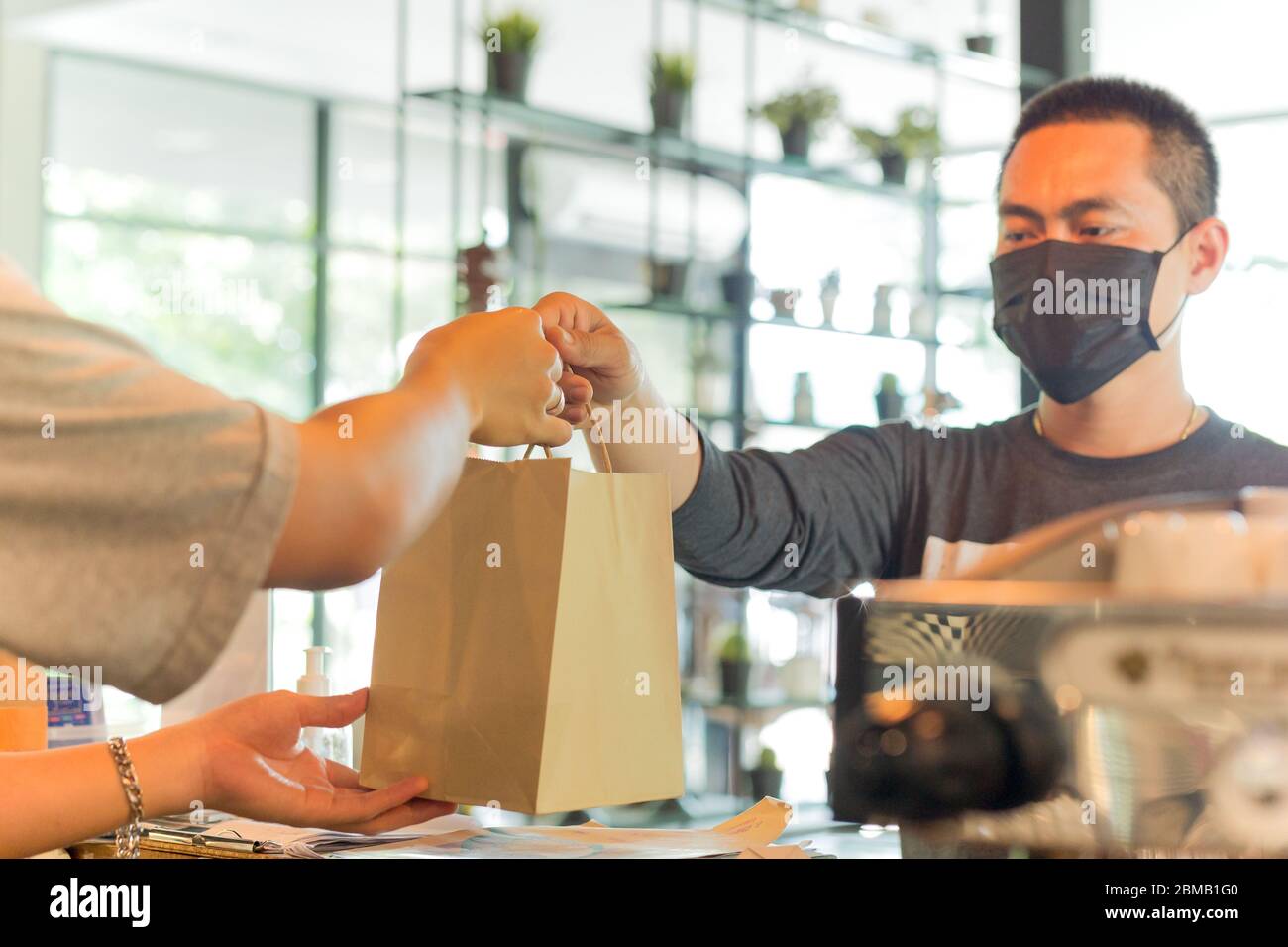 Social distance conceptual waiter giving takeaway bag to customer at ...
