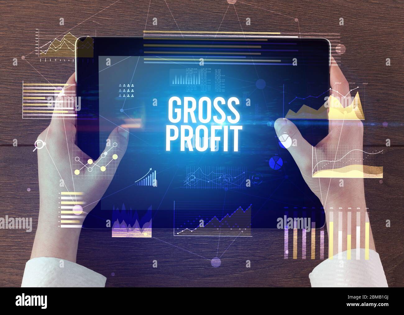 Close-up of hands holding tablet with GROSS PROFIT inscription, modern ...