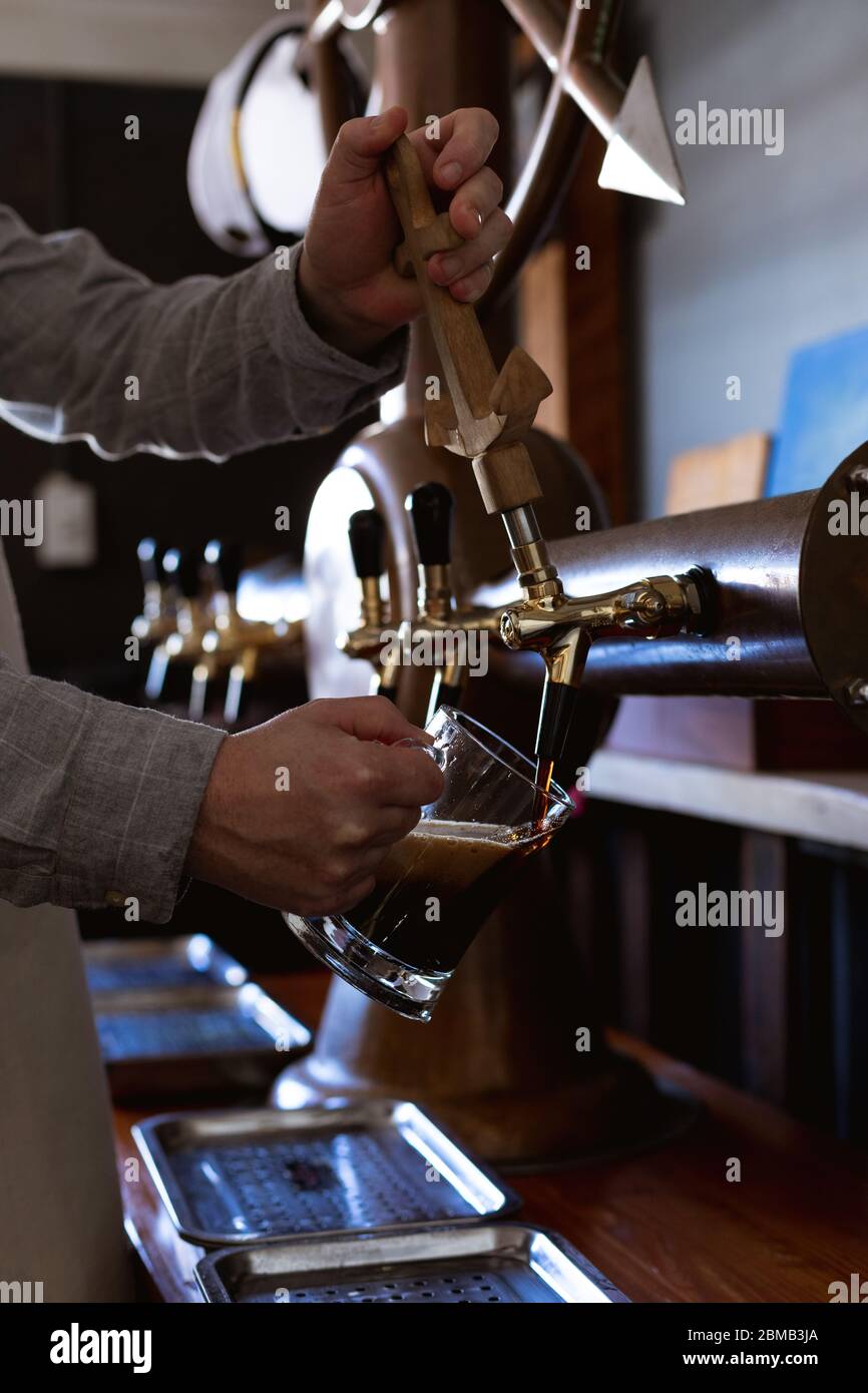 Caucasian man serving a pint of beer in a brewery Stock Photo - Alamy