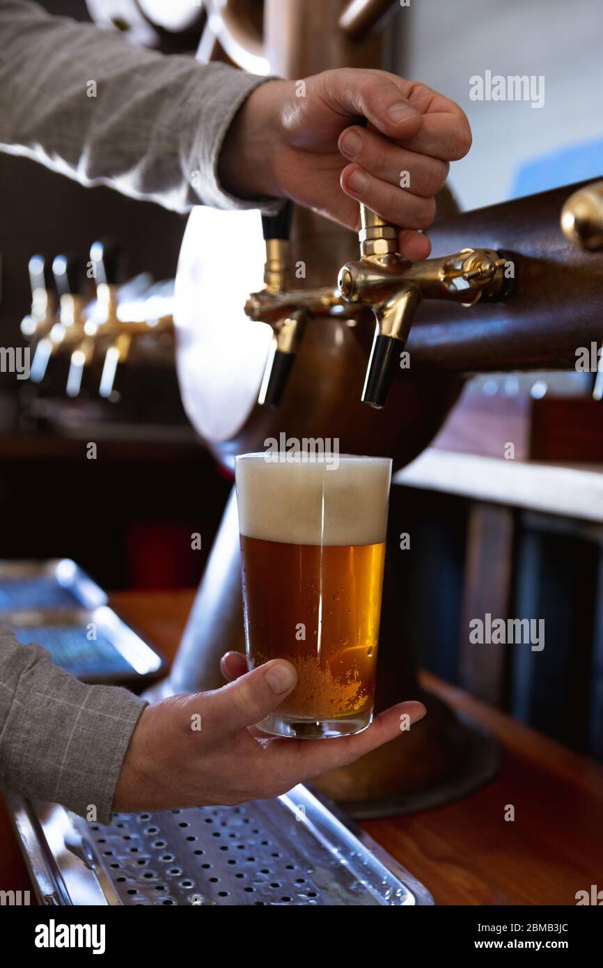 Caucasian man serving a pint of beer in a brewery Stock Photo - Alamy