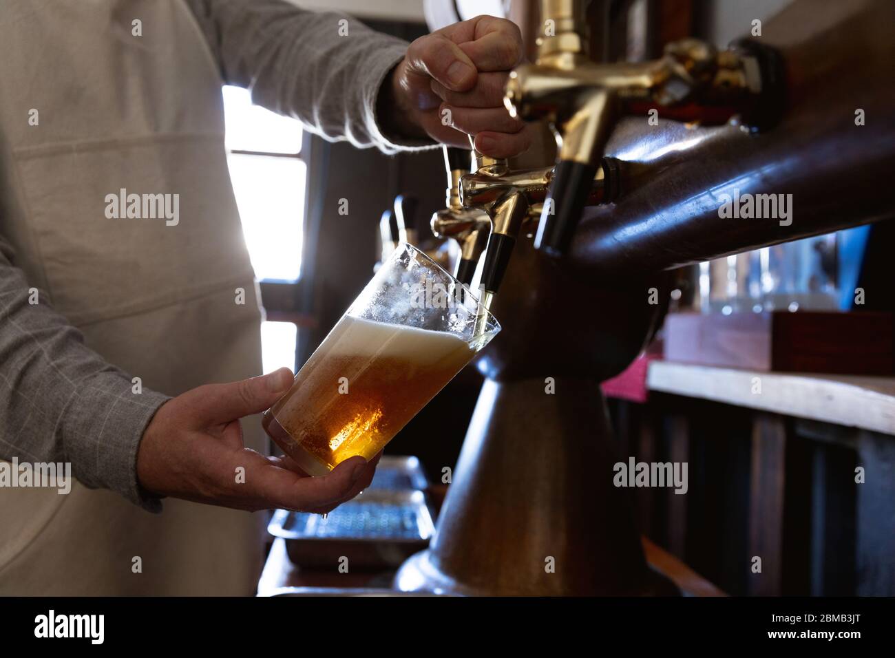 Caucasian man serving a pint of beer in a brewery Stock Photo - Alamy
