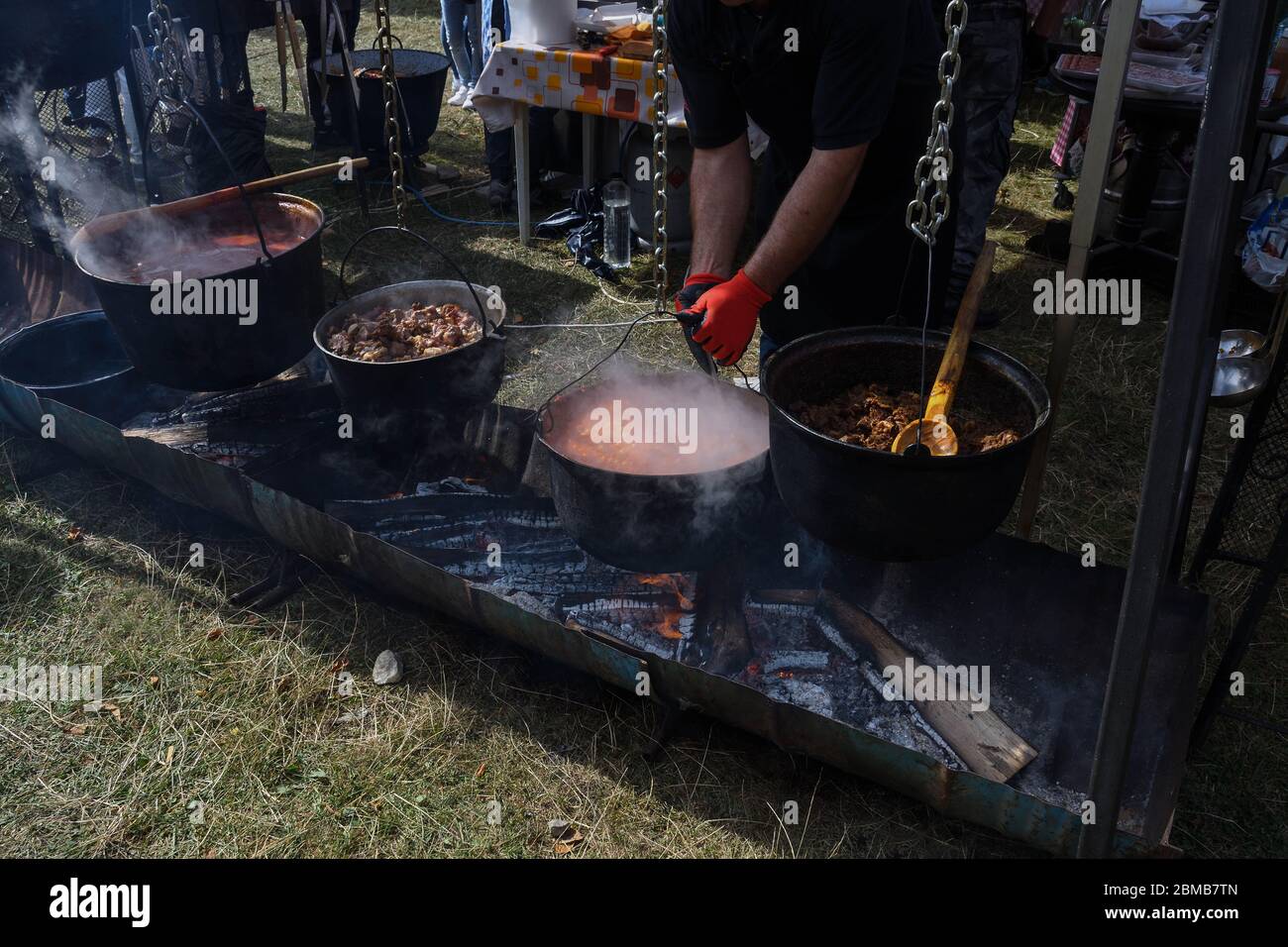 Very large cauldron cooking food during campfire, big pots on fire ...