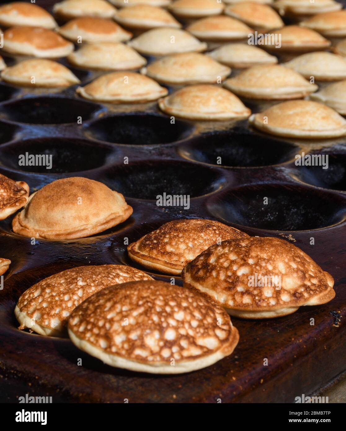 Typical Dutch poffertjes - tiny pancakes-being baked on a heavy cast ...