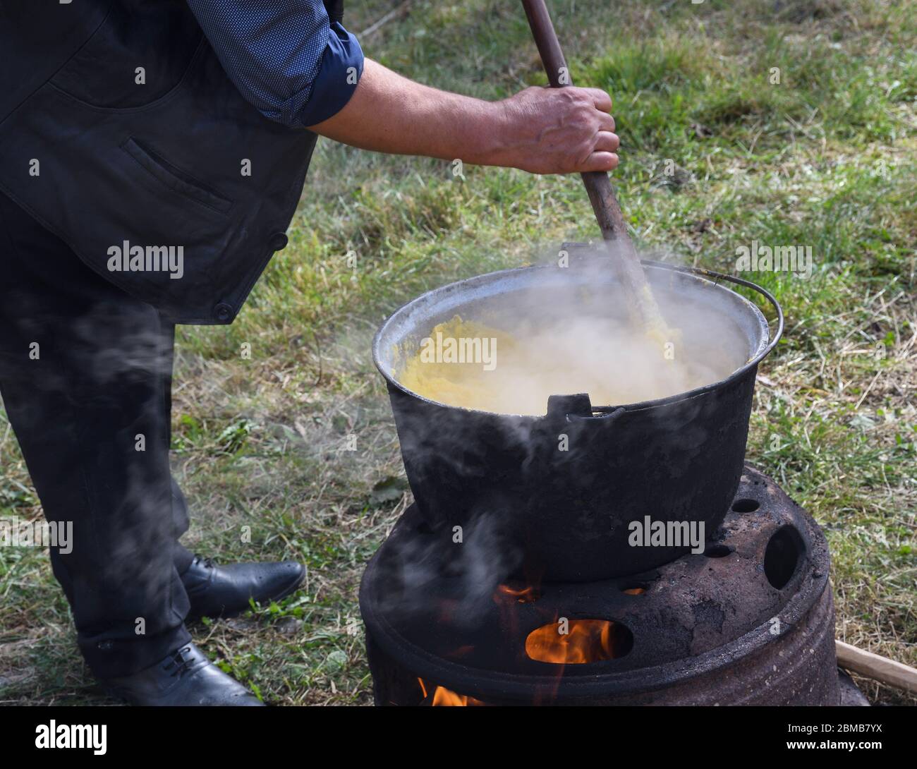 Very large cauldron cooking food during campfire, big pots on fire ...