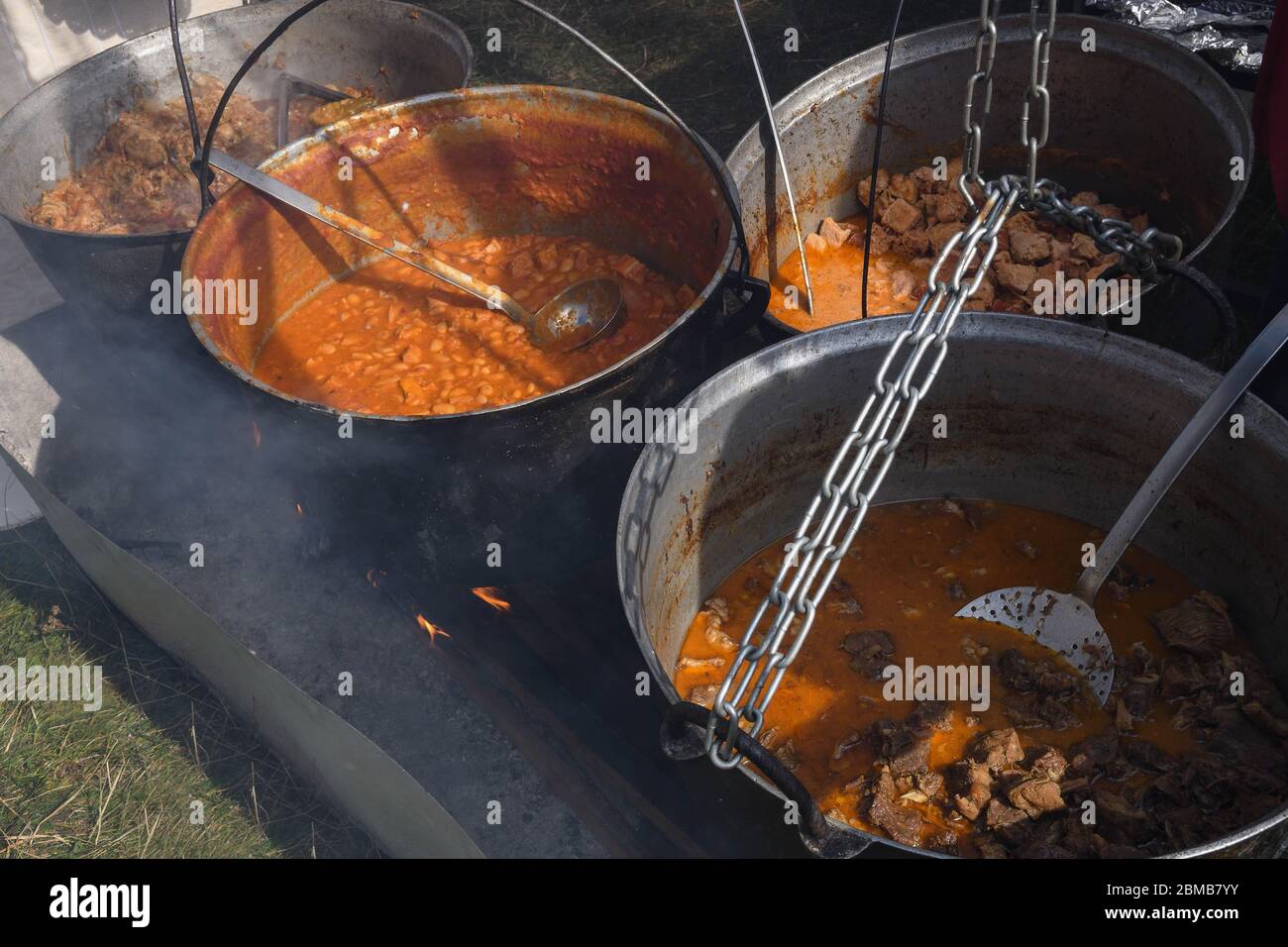 Very large cauldron cooking food during campfire, big pots on fire ...