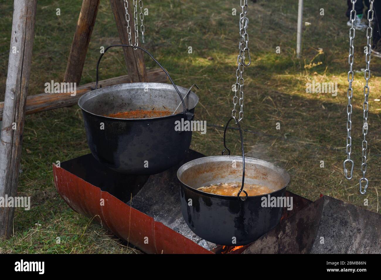 Very large cauldron cooking food during campfire, big pots on fire ...