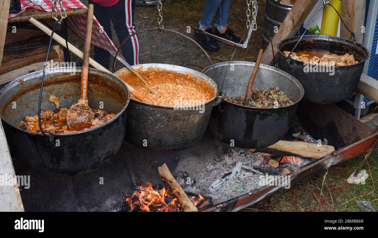 Very large cauldron cooking food during campfire, big pots on fire ...
