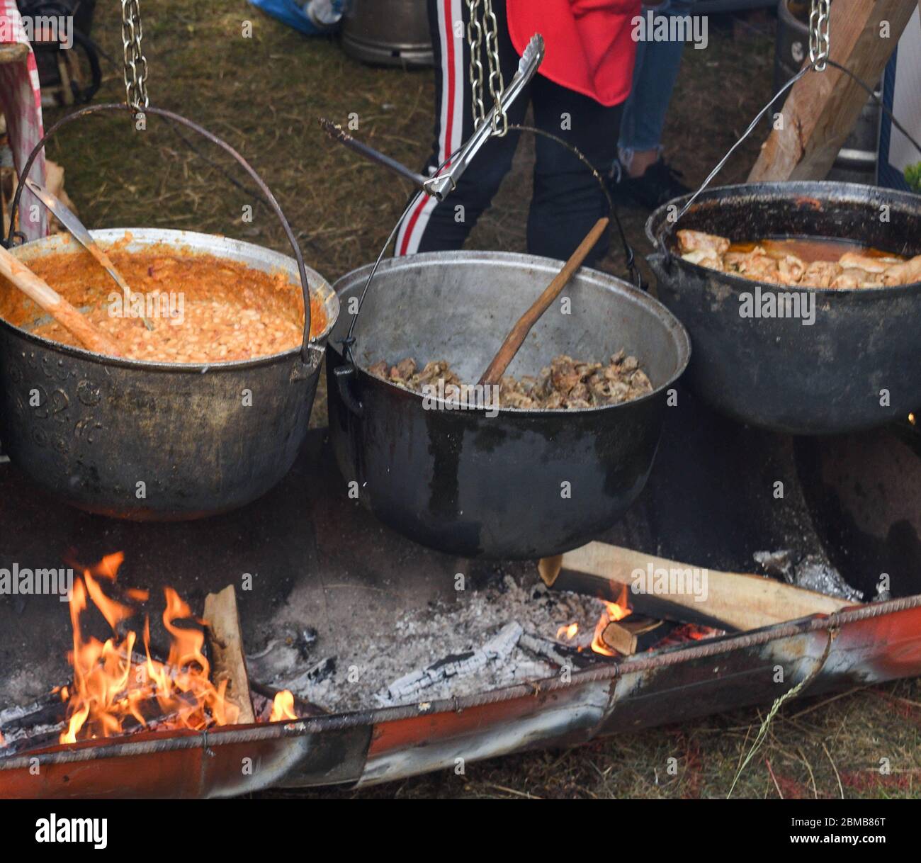 Very large cauldron cooking food during campfire, big pots on fire ...