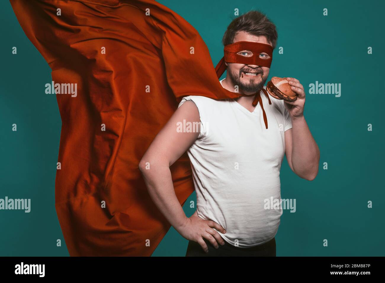 Hungry super hero man eating a hamburger, super hero or antihero in a ...