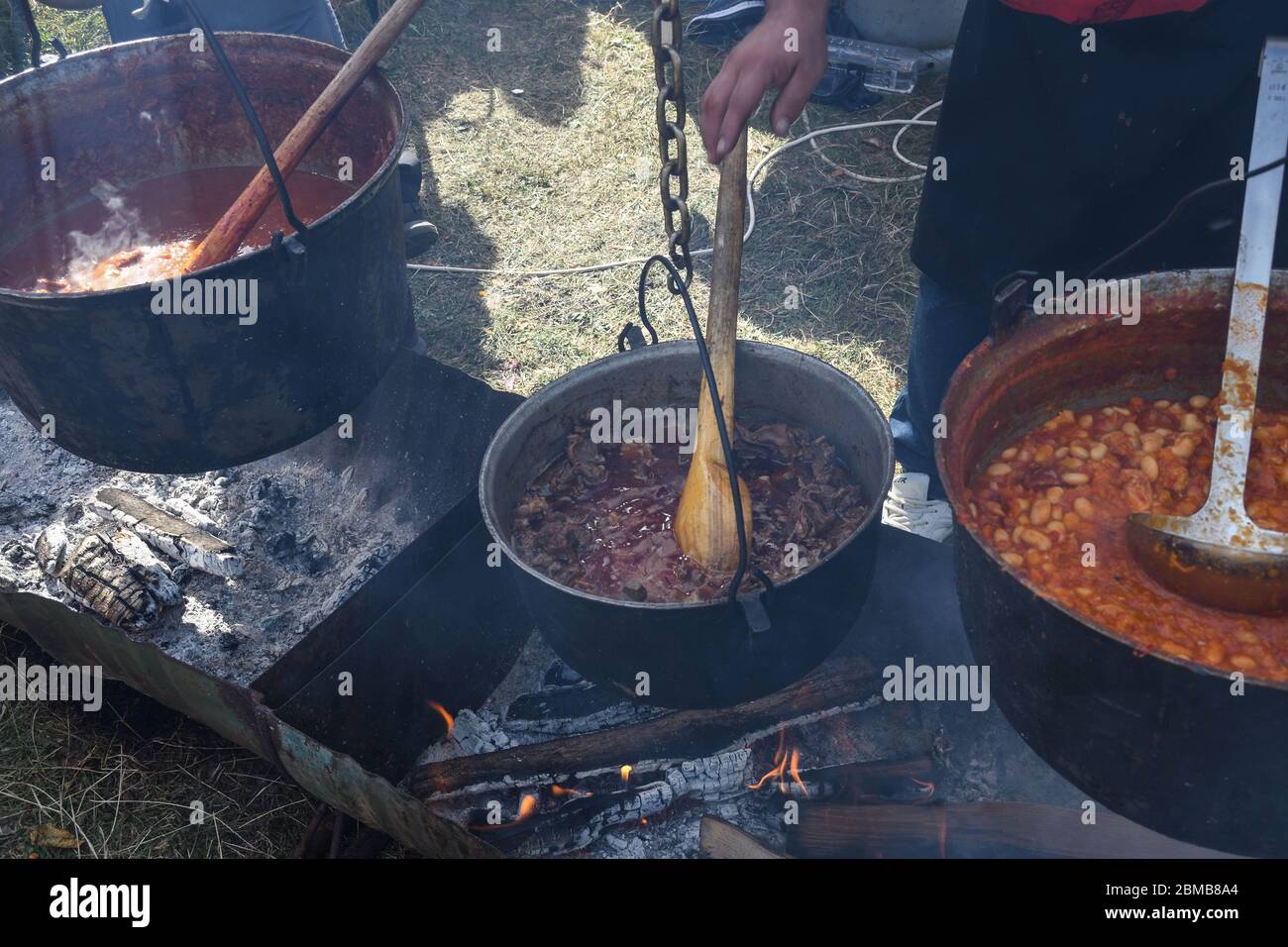 Very large cauldron cooking food during campfire, big pots on fire ...