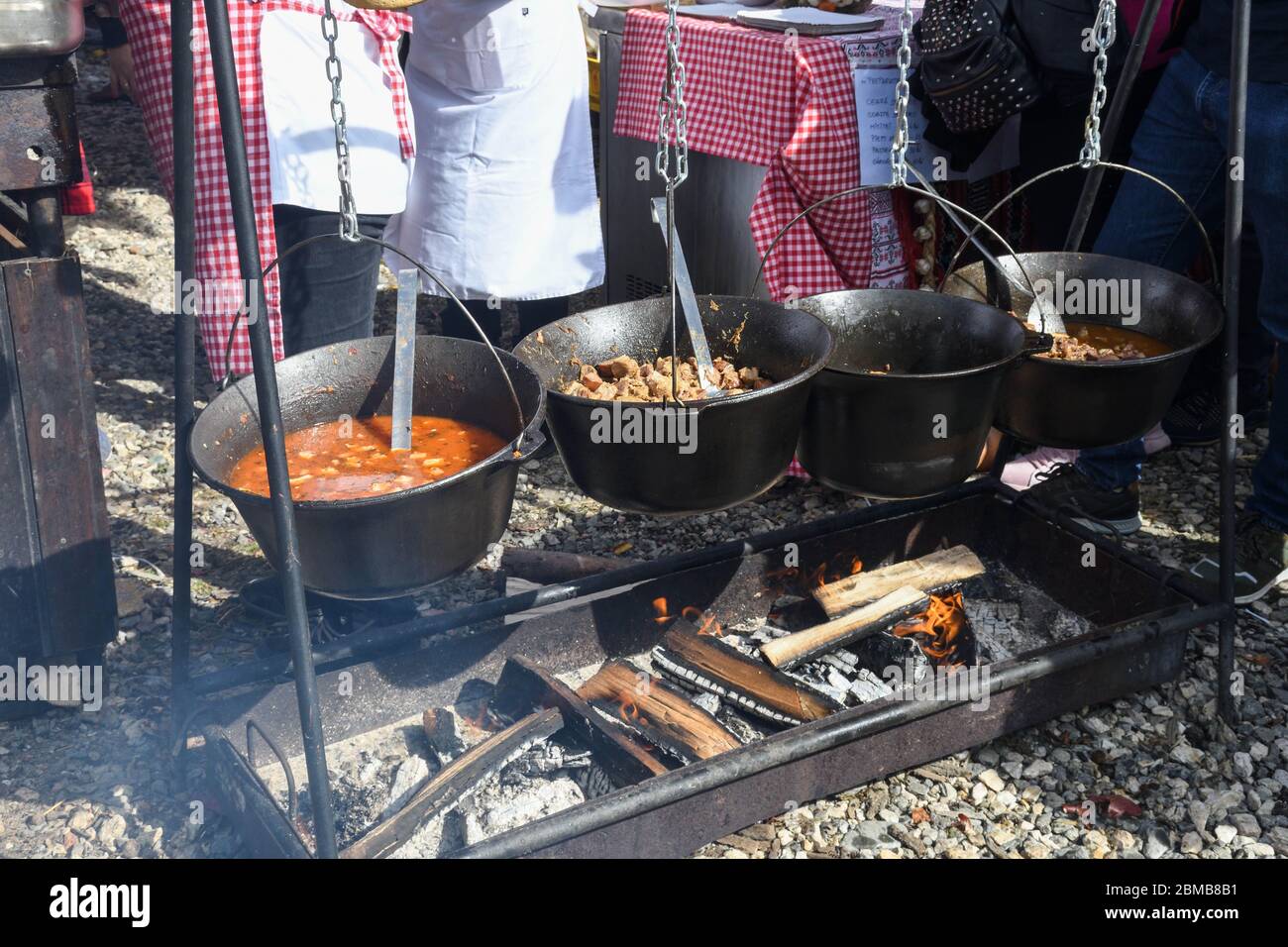 Very large cauldron cooking food during campfire, big pots on fire ...