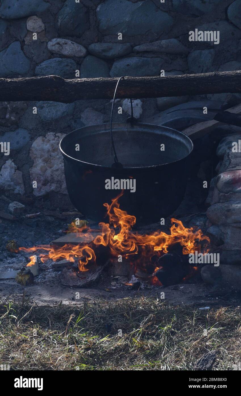 Very large cauldron cooking food during campfire, big pots on fire ...