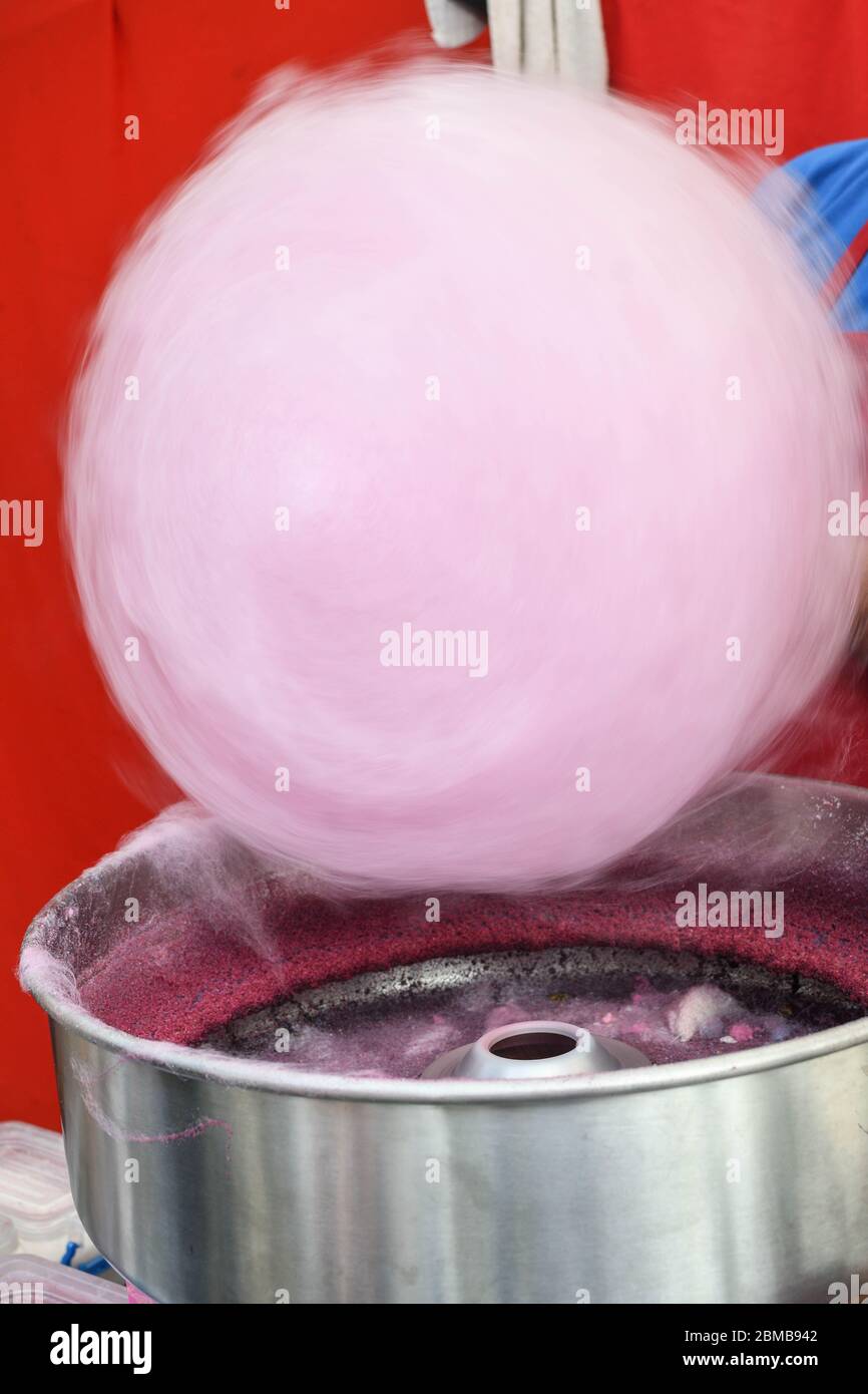 Hand rolling cotton candy in candy floss machine. Making candyfloss ...