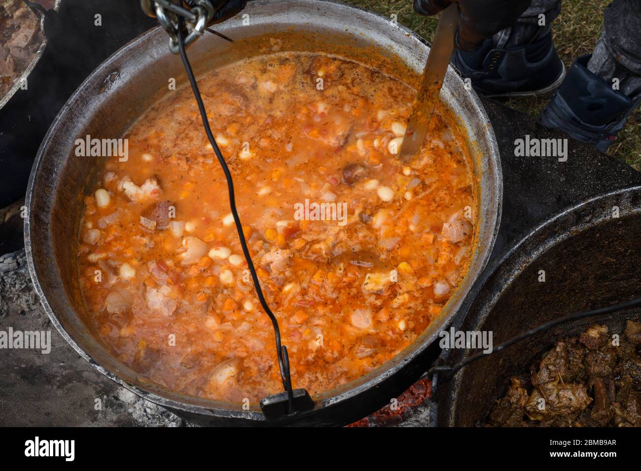 Very large cauldron cooking food during campfire, big pots on fire ...