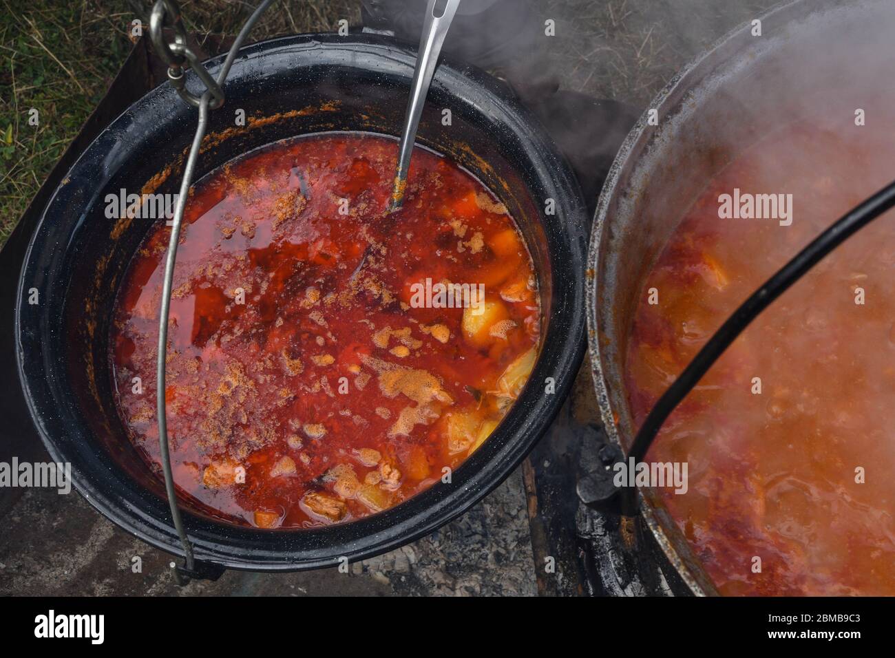 Very large cauldron cooking food during campfire, big pots on fire ...