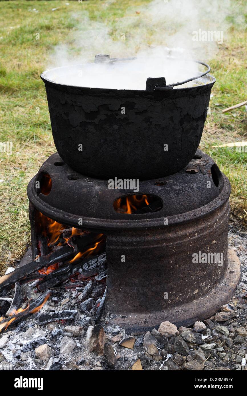 Very large cauldron cooking food during campfire, big pots on fire ...