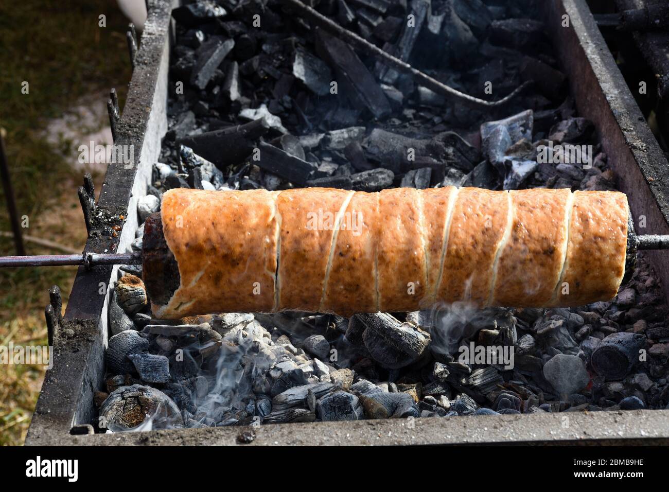 Kurtos kalacs or chimney cakes, preparing cooking on charcoal grill ...