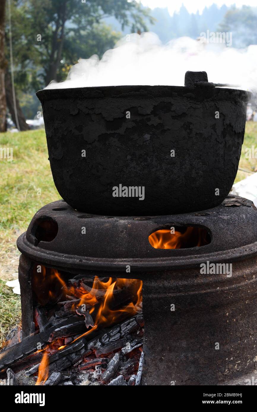 Very large cauldron cooking food during campfire, big pots on fire ...