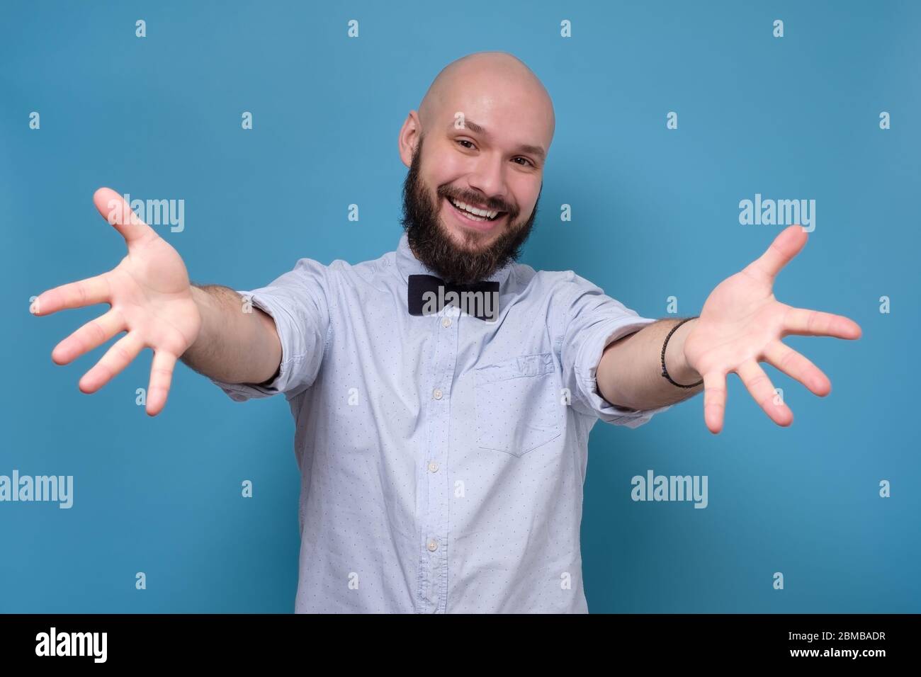 Happy casual friendly man showing greeting gesture isolated on a blue ...