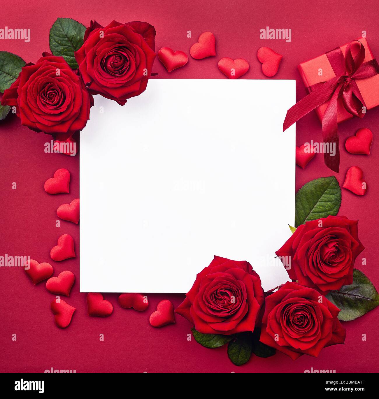 Creative frame of red roses, gift box and hearts with blank paper note ...