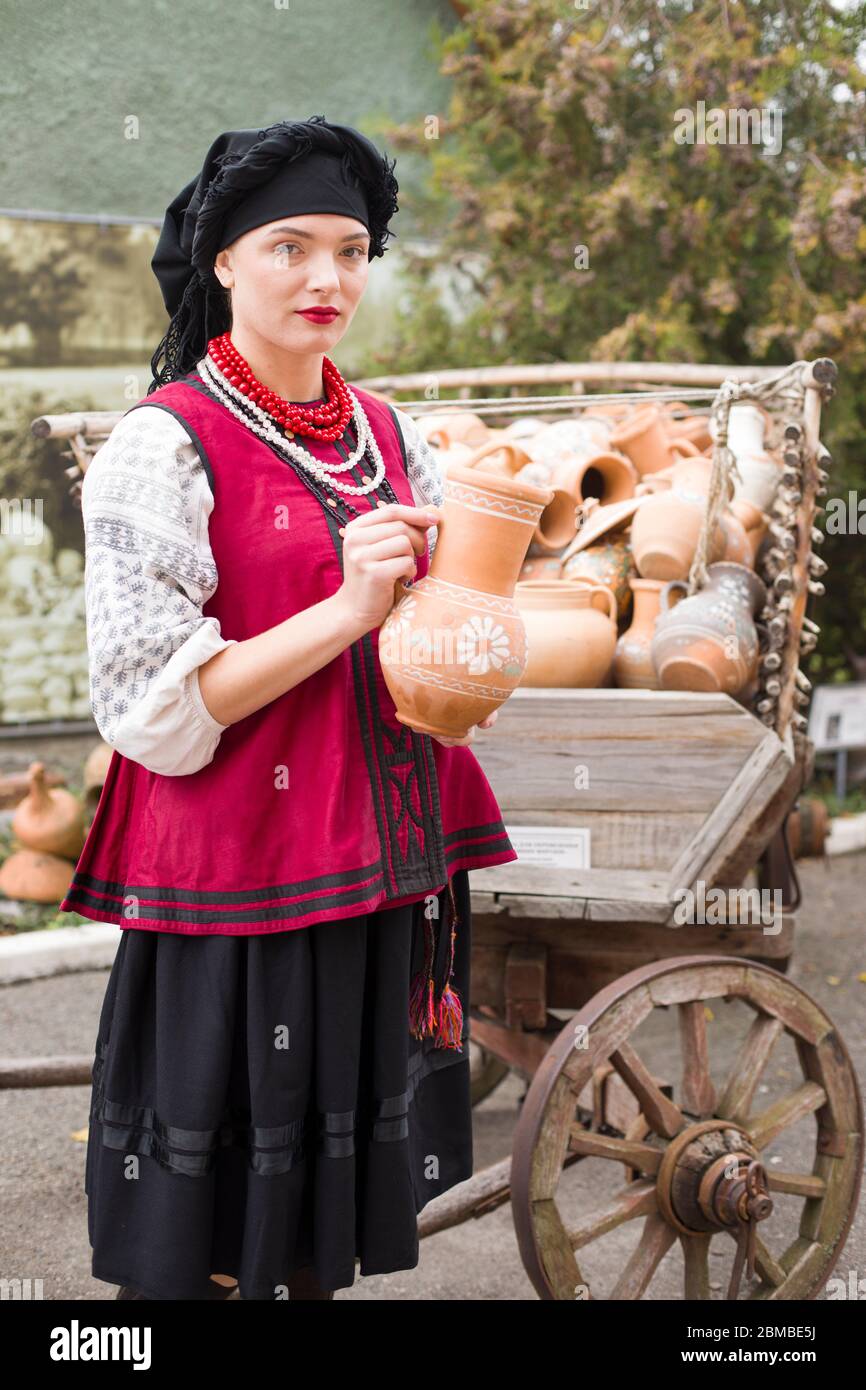 Beautiful girl in national dress. Holding an ancient pot in his hands ...