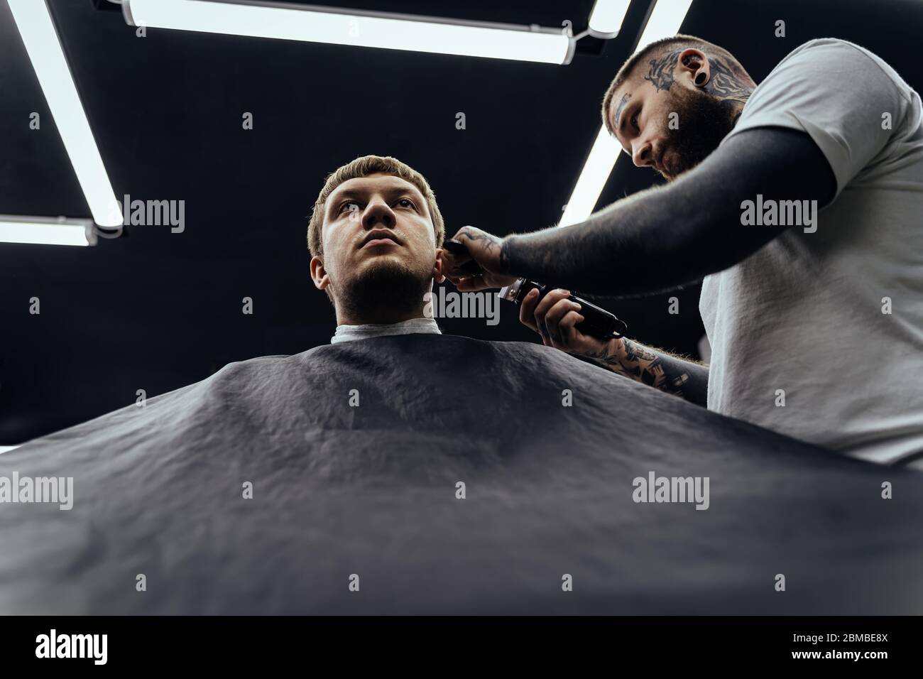 Male haircut with electric razor. Tattooed Barber makes haircut for ...