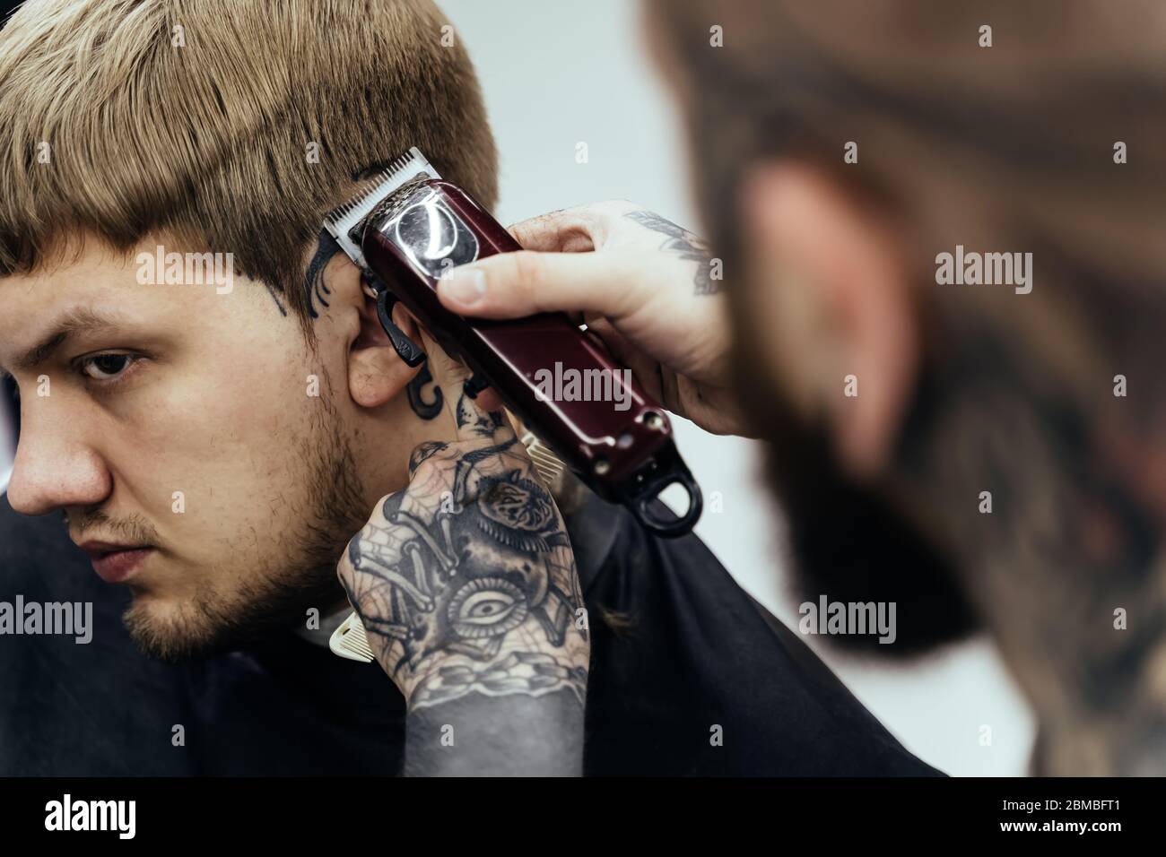 Male haircut with electric razor. Tattooed Barber makes haircut for ...