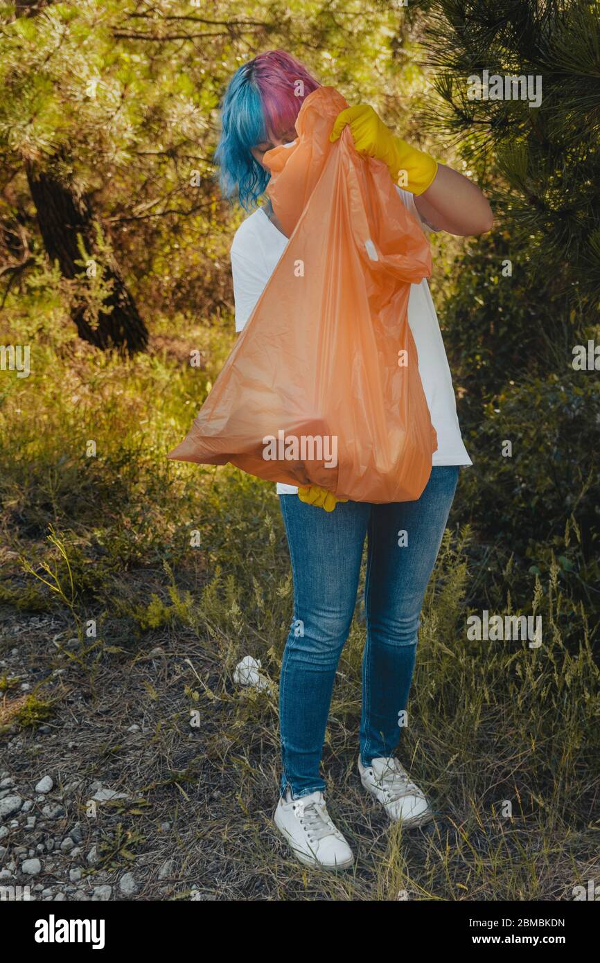 A young female collecting the trash and putting in a plastic garbage ...