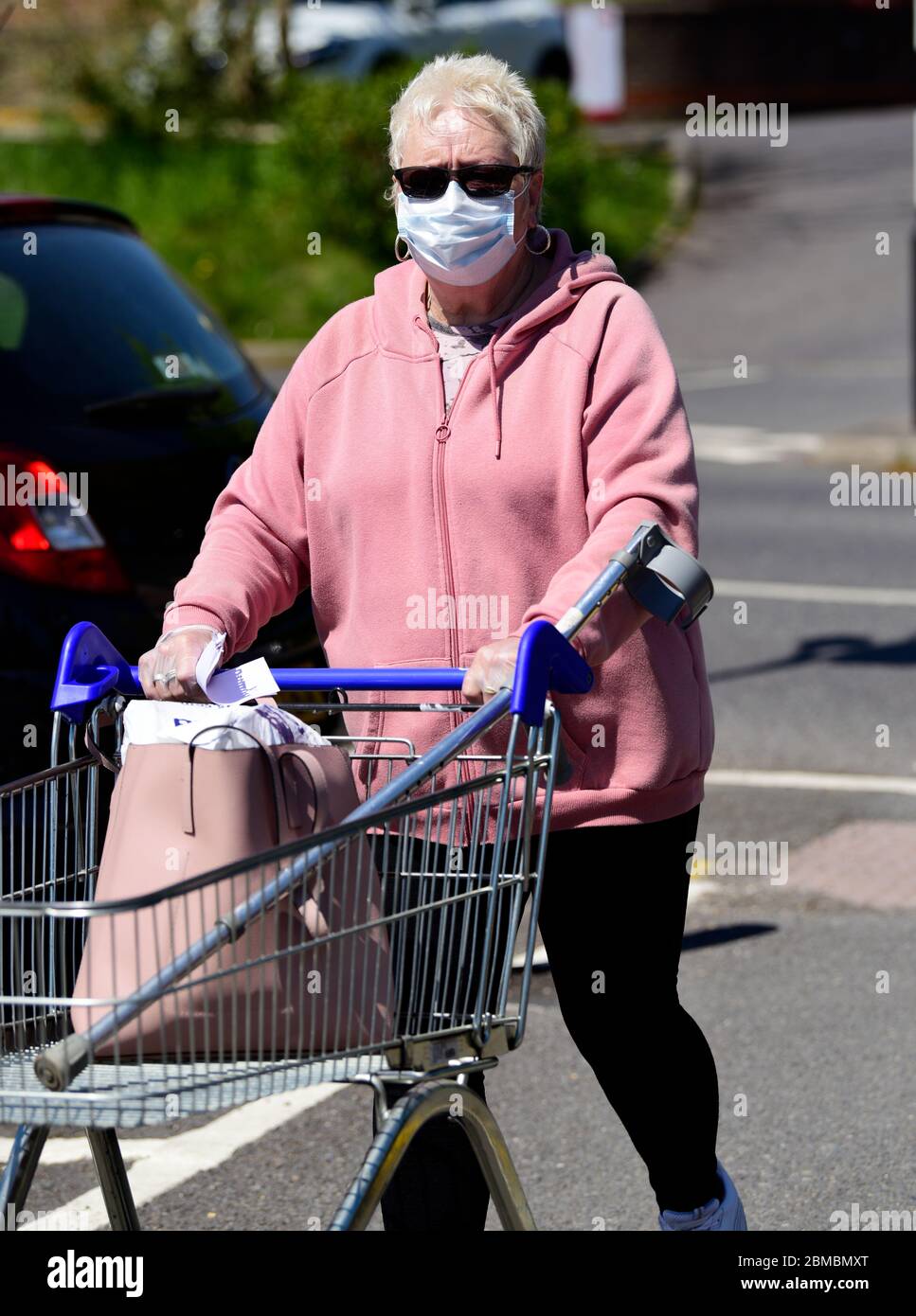Elderly woman with shopping trolley en route to supermarket wearing ...