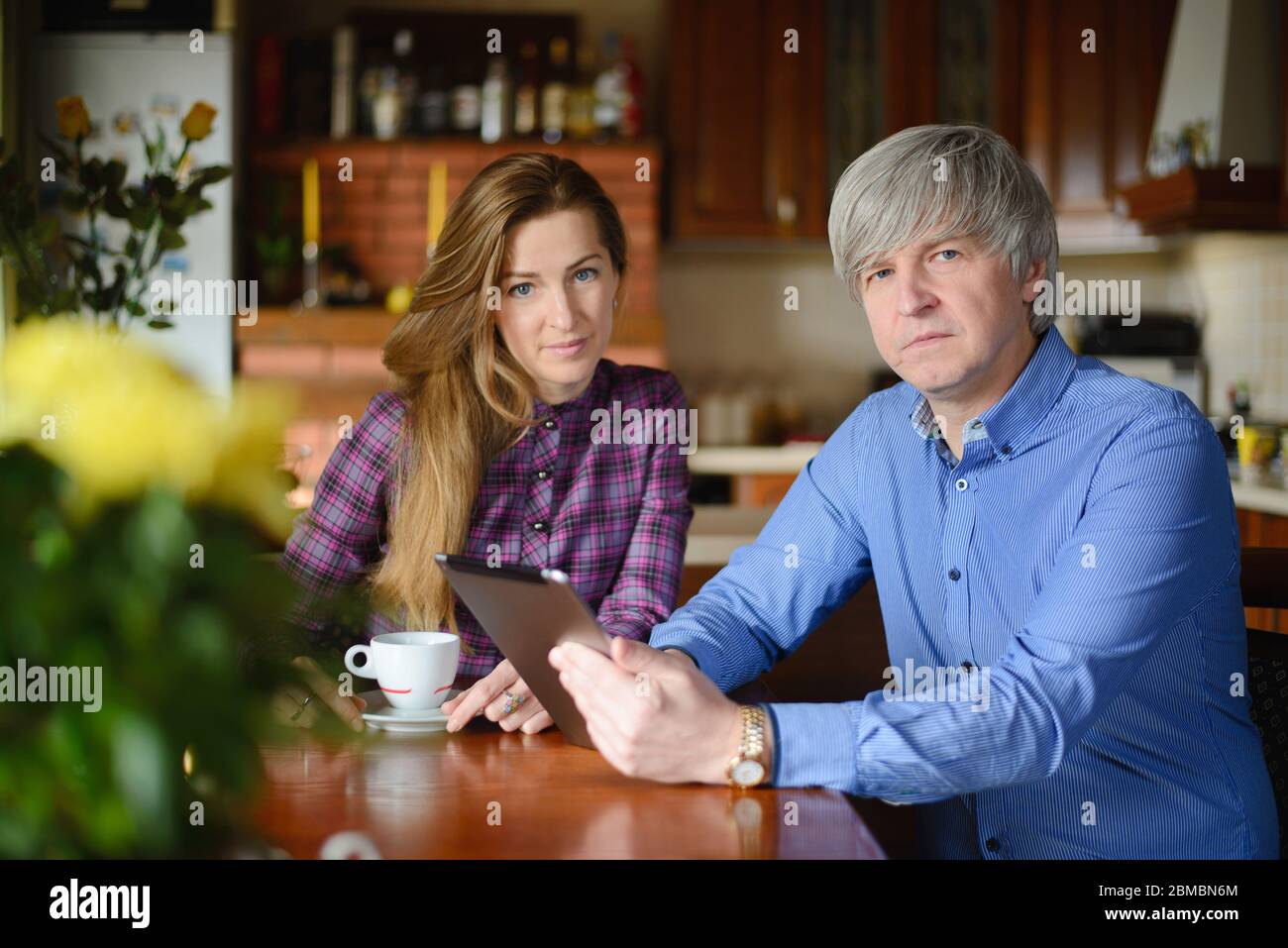 Adult couple sitting at table with laptop Stock Photo - Alamy