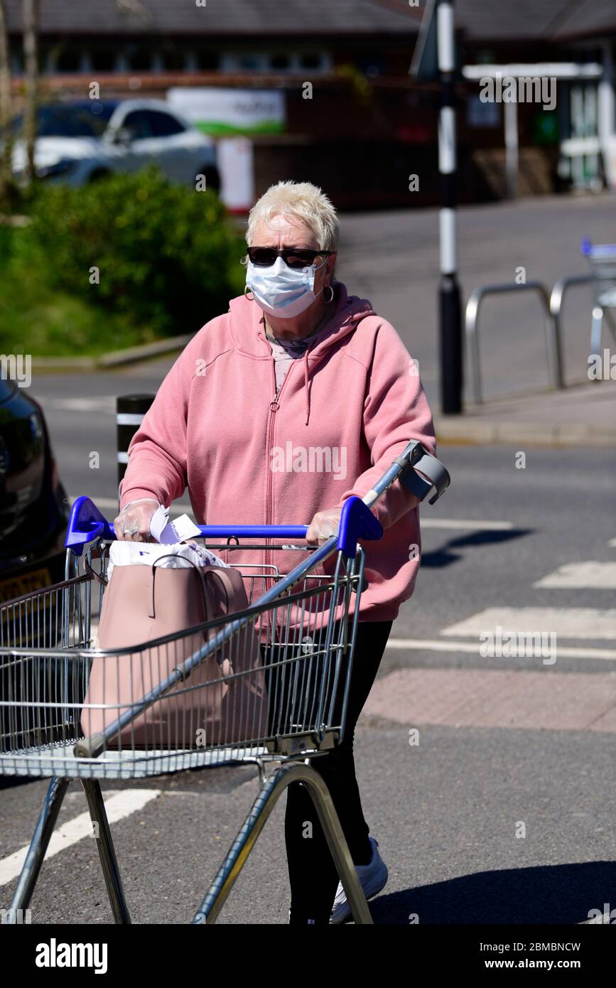 Elderly woman with shopping trolley en route to supermarket wearing ...