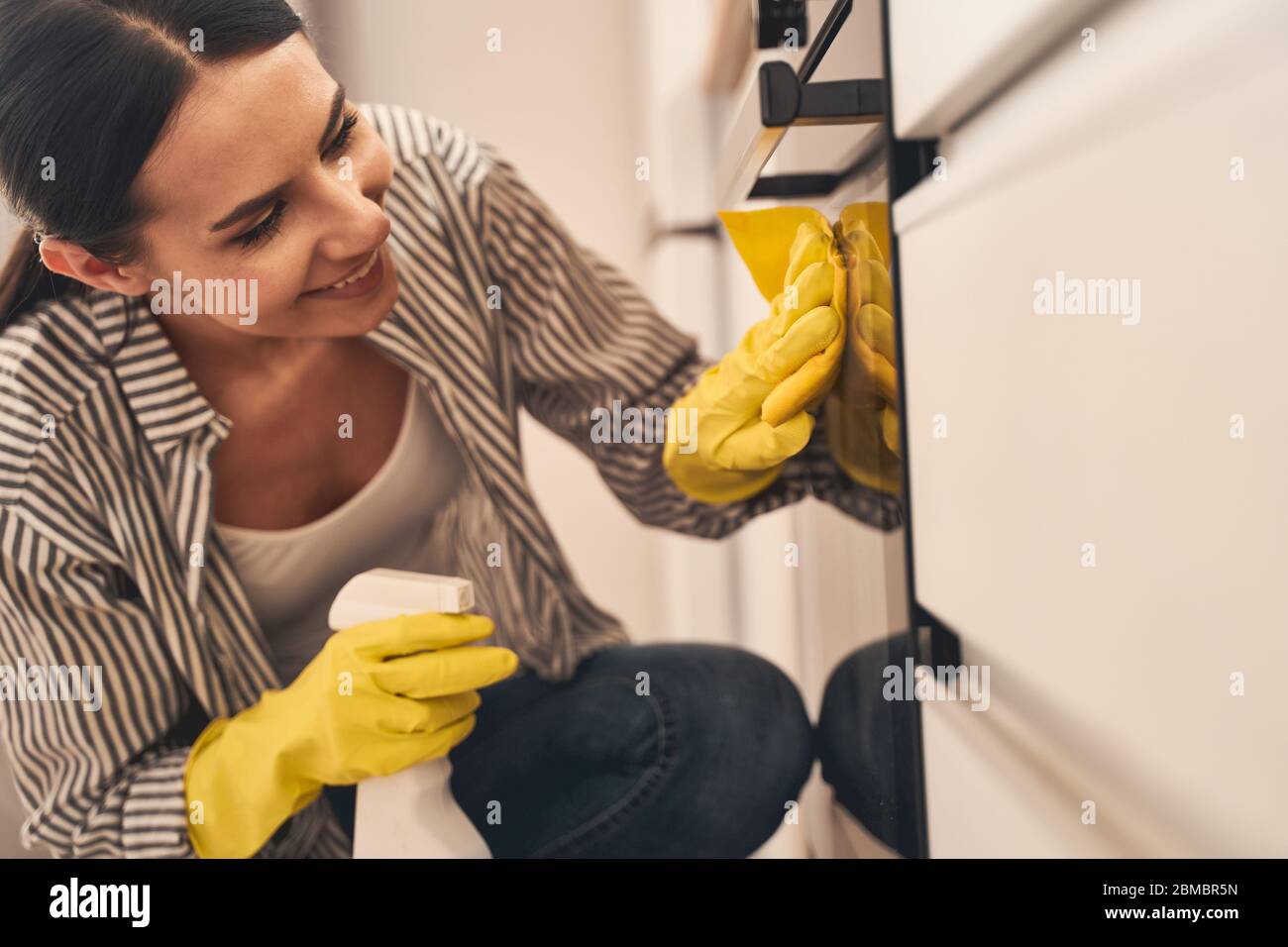Cheerful young female person wiping glass surface Stock Photo - Alamy
